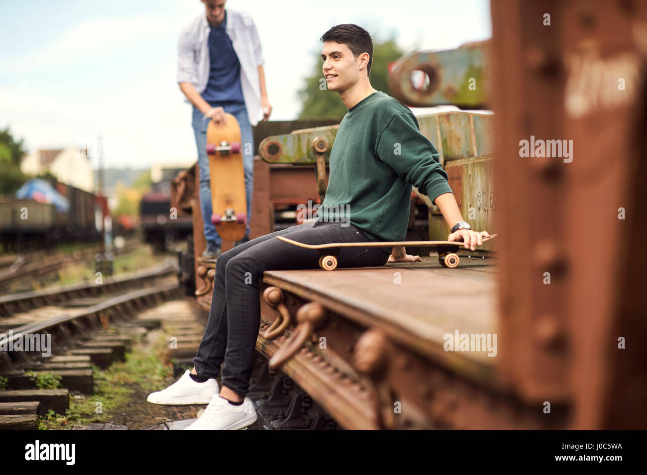 Two young men by train track, carrying skateboard, Bristol, UK Stock ...