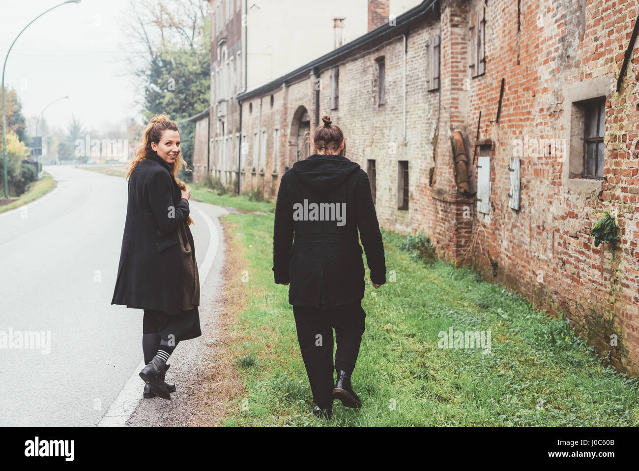 Young woman looking back while strolling with boyfriend on rural road ...