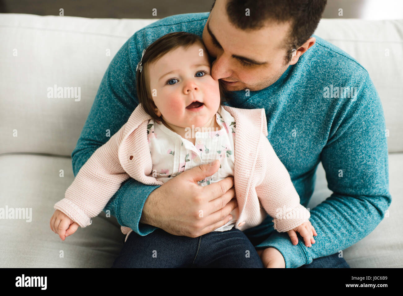 Baby girl looking up while being snuggled by her father Stock Photo - Alamy