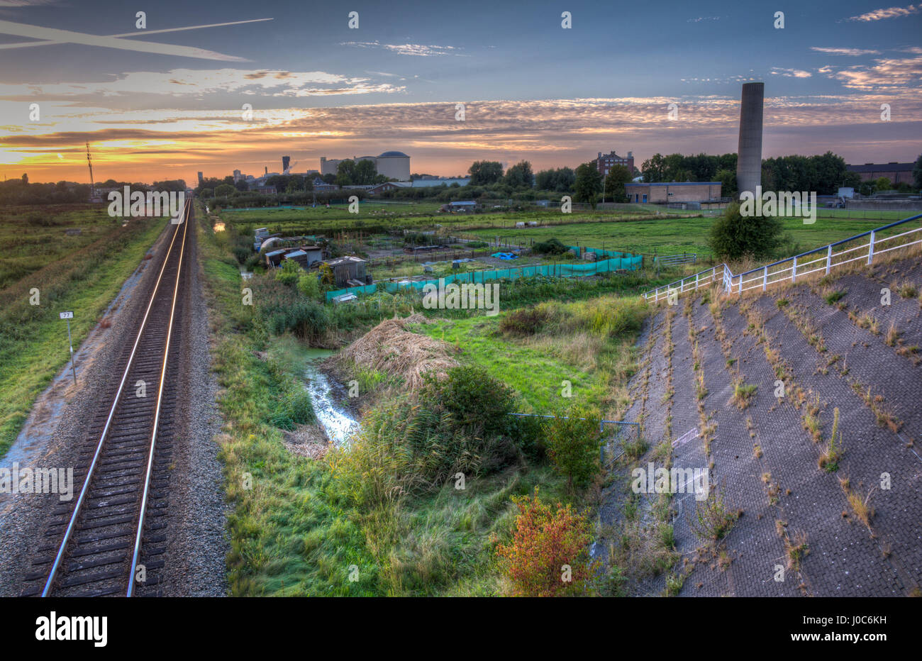 A train track going into the industry city buildings at sunset in ...
