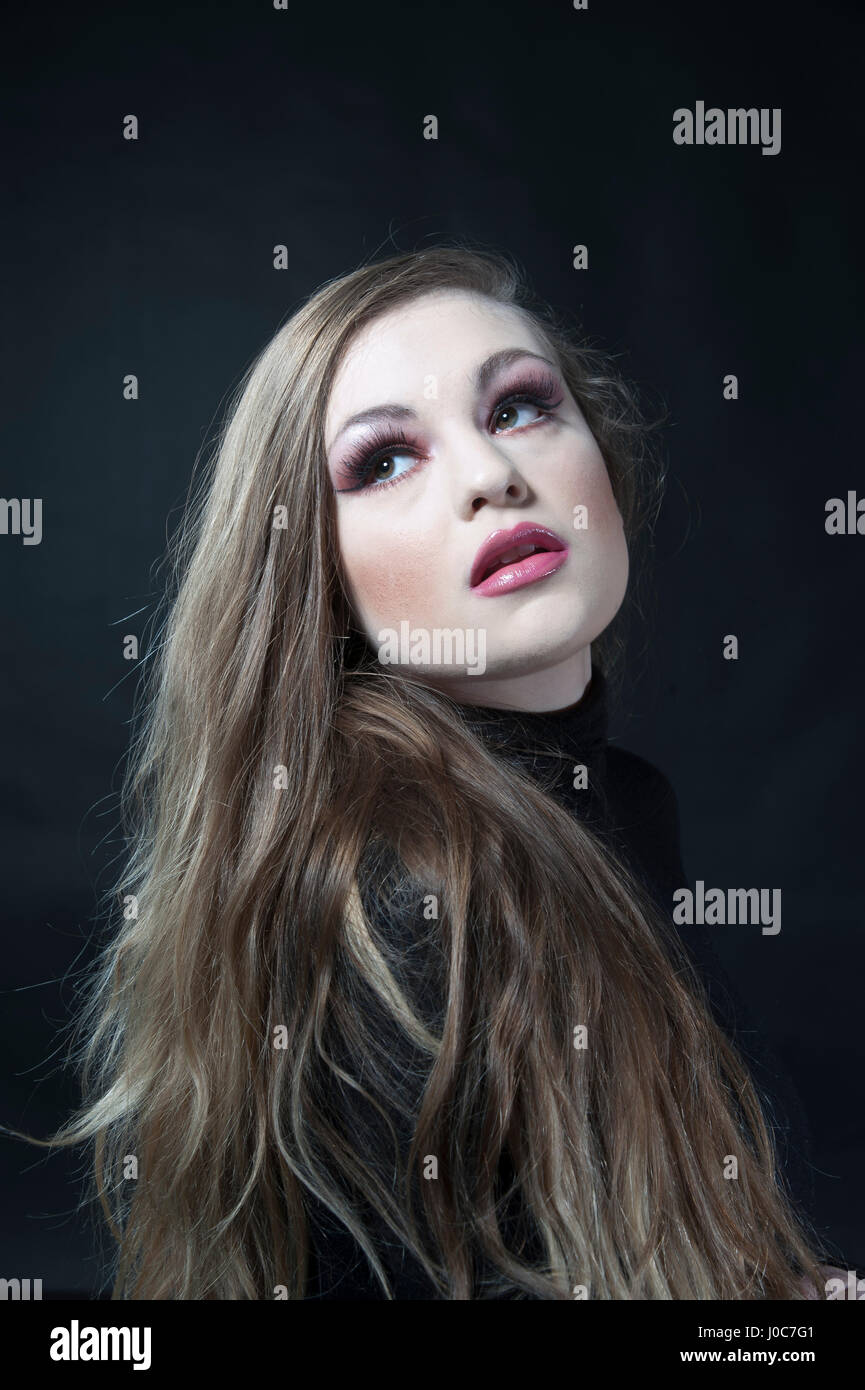 Portrait of young woman with long fair hair wearing a black top and ...