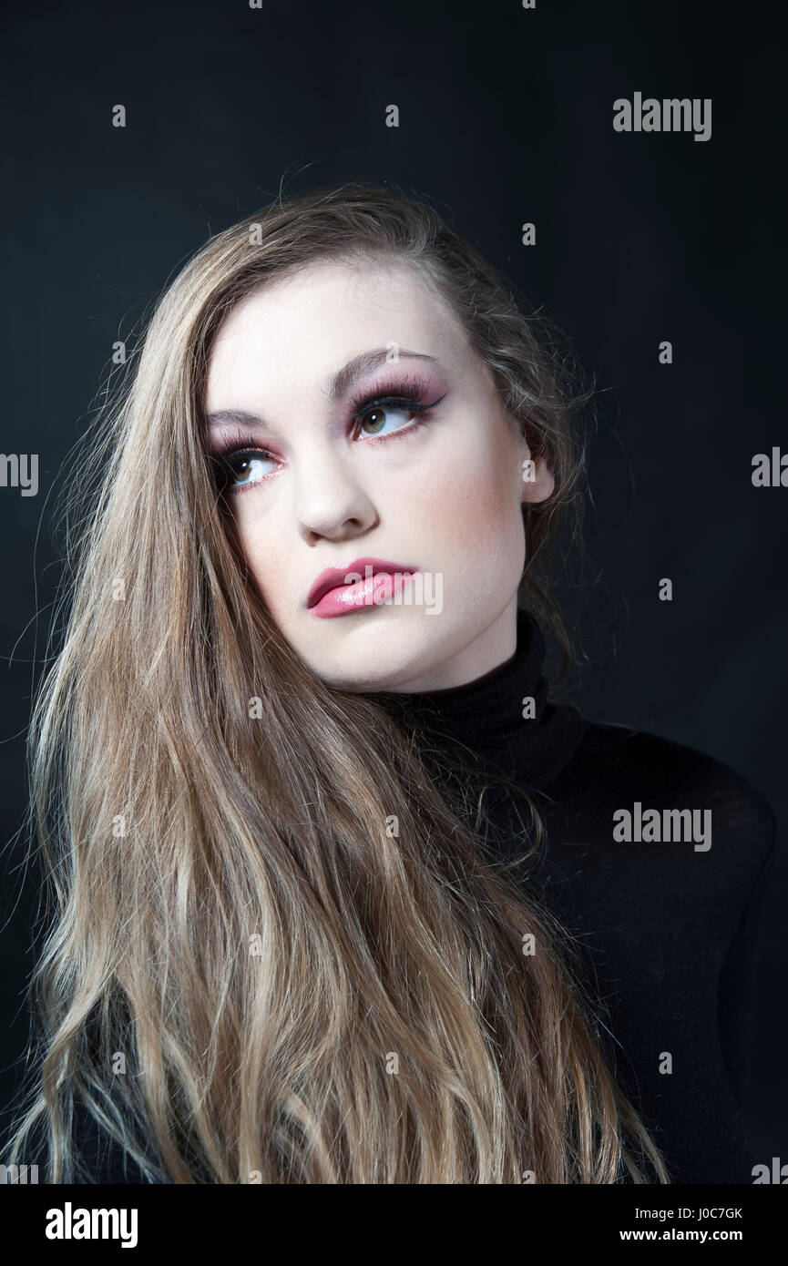 Portrait of young woman with long fair hair wearing a black top and ...