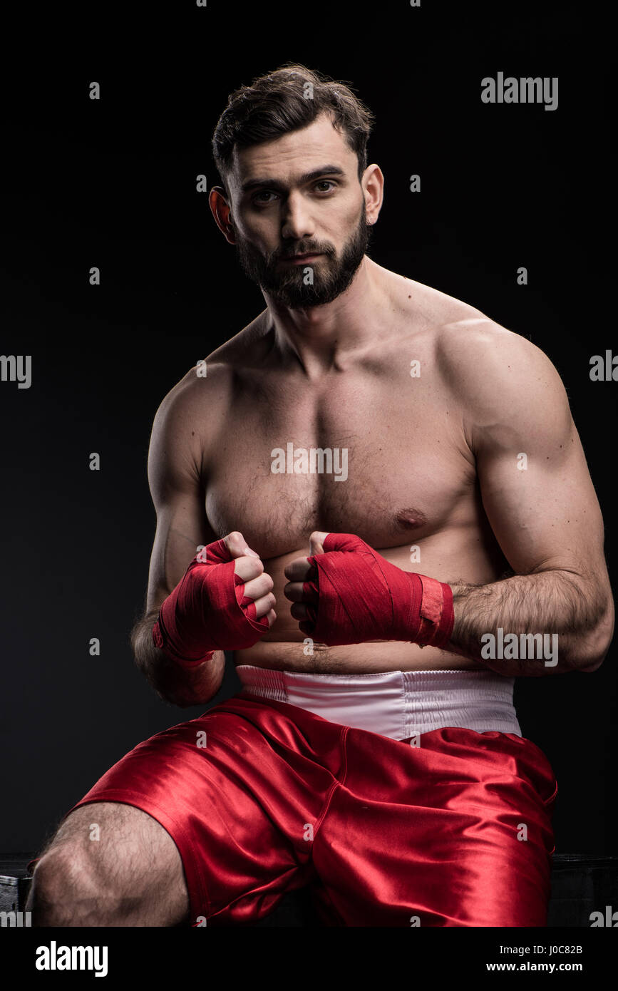 Portrait of muscular bearded boxer with wrapping hands looking at ...
