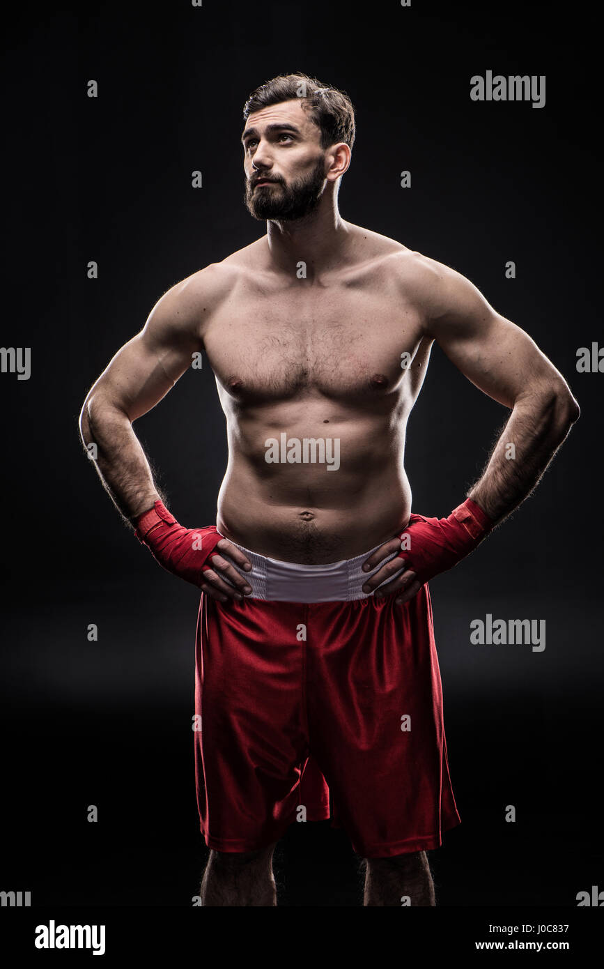 Young muscular bearded boxer with wrapping hands standing and looking ...