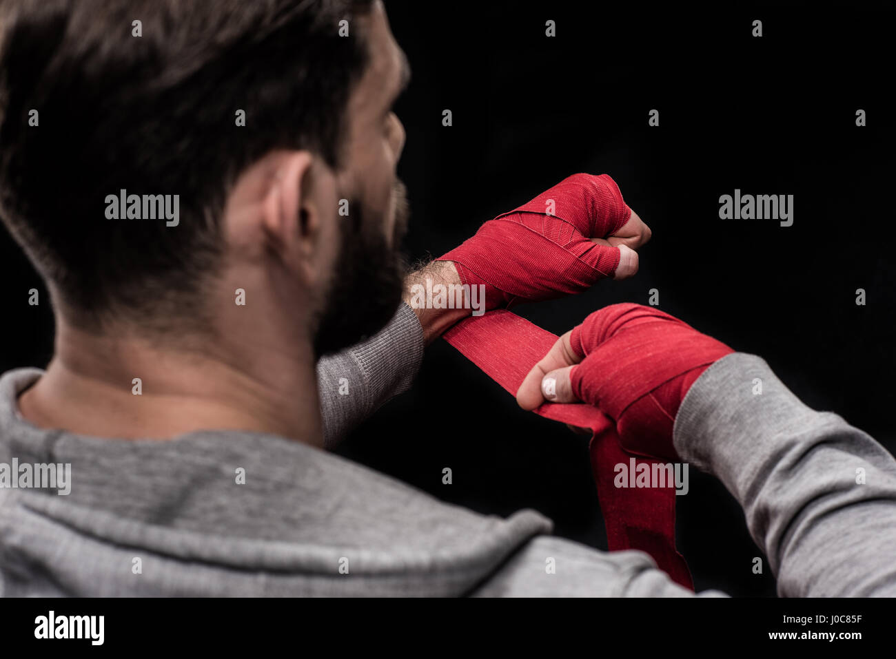 Rear view or boxer wrapping hands with red tape on black Stock Photo ...