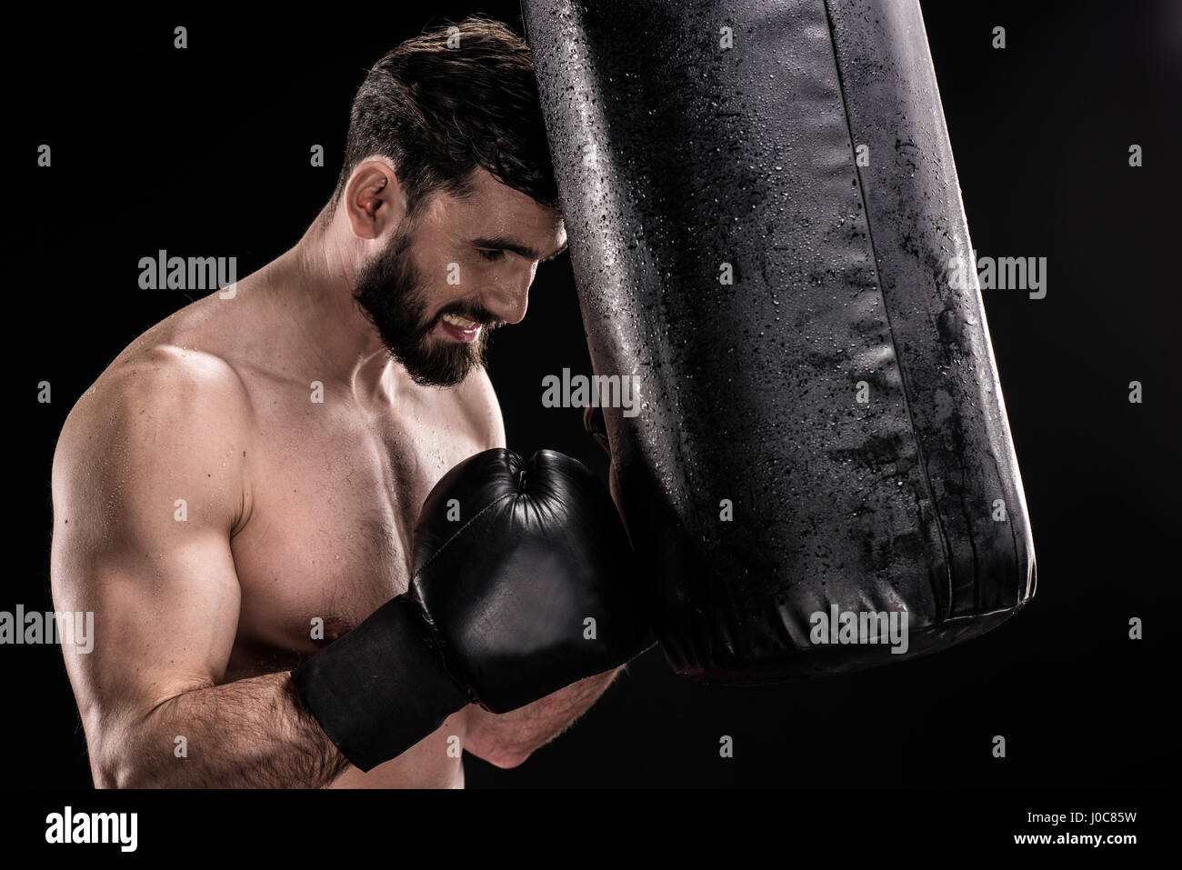 Young stressed boxer touching punching bag with forehead and hands in ...