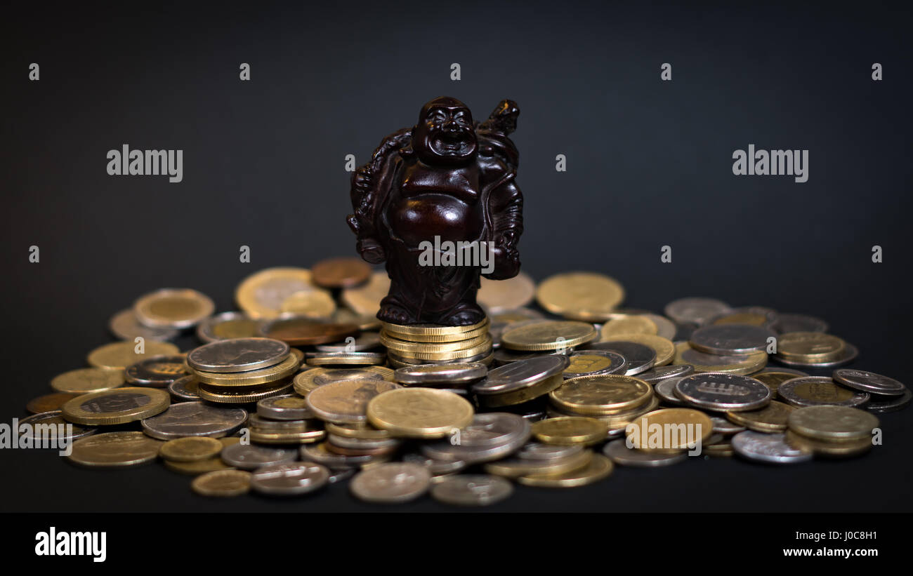 Little Buddha statue sitting on a big pile of coins bringing good luck ...