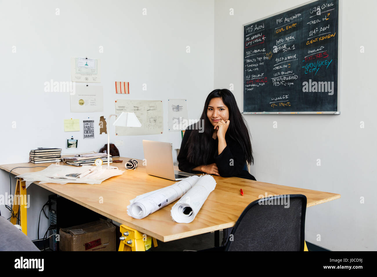 Woman sitting at desk in office working on laptop Stock Photo - Alamy