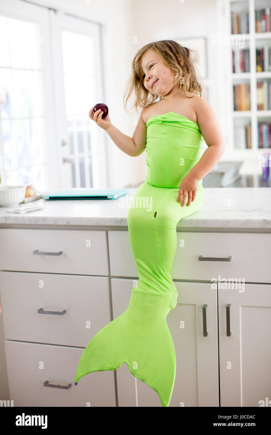 Girl in lime green mermaid costume sitting on kitchen counter Stock ...