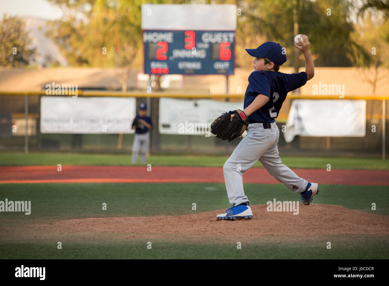 Boy baseball pitcher throwing ball on baseball field Stock Photo - Alamy