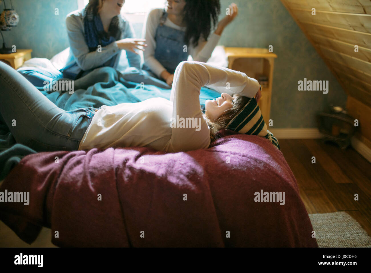 Three female friends, relaxing in bedroom, laughing Stock Photo - Alamy