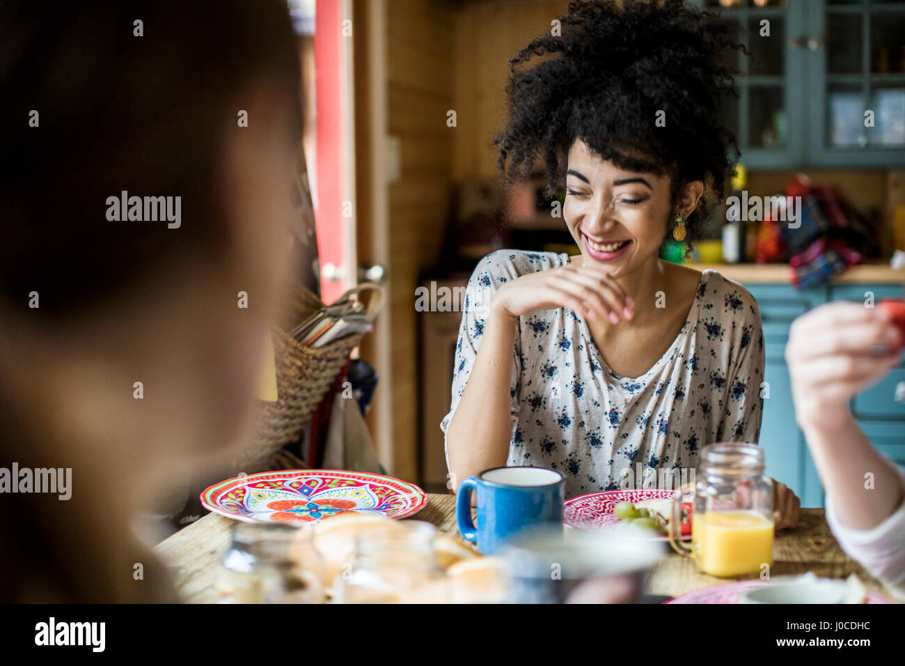 Three friends sitting around table, eating breakfast Stock Photo - Alamy