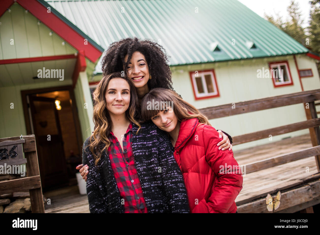 Portrait of three friends standing in front of cabin Stock Photo - Alamy