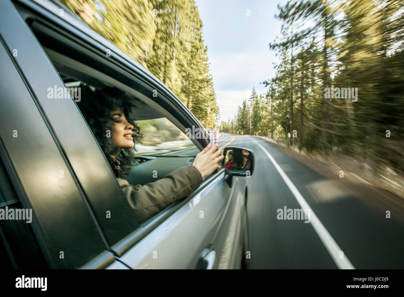 Young woman taking photograph from window of moving car Stock Photo - Alamy