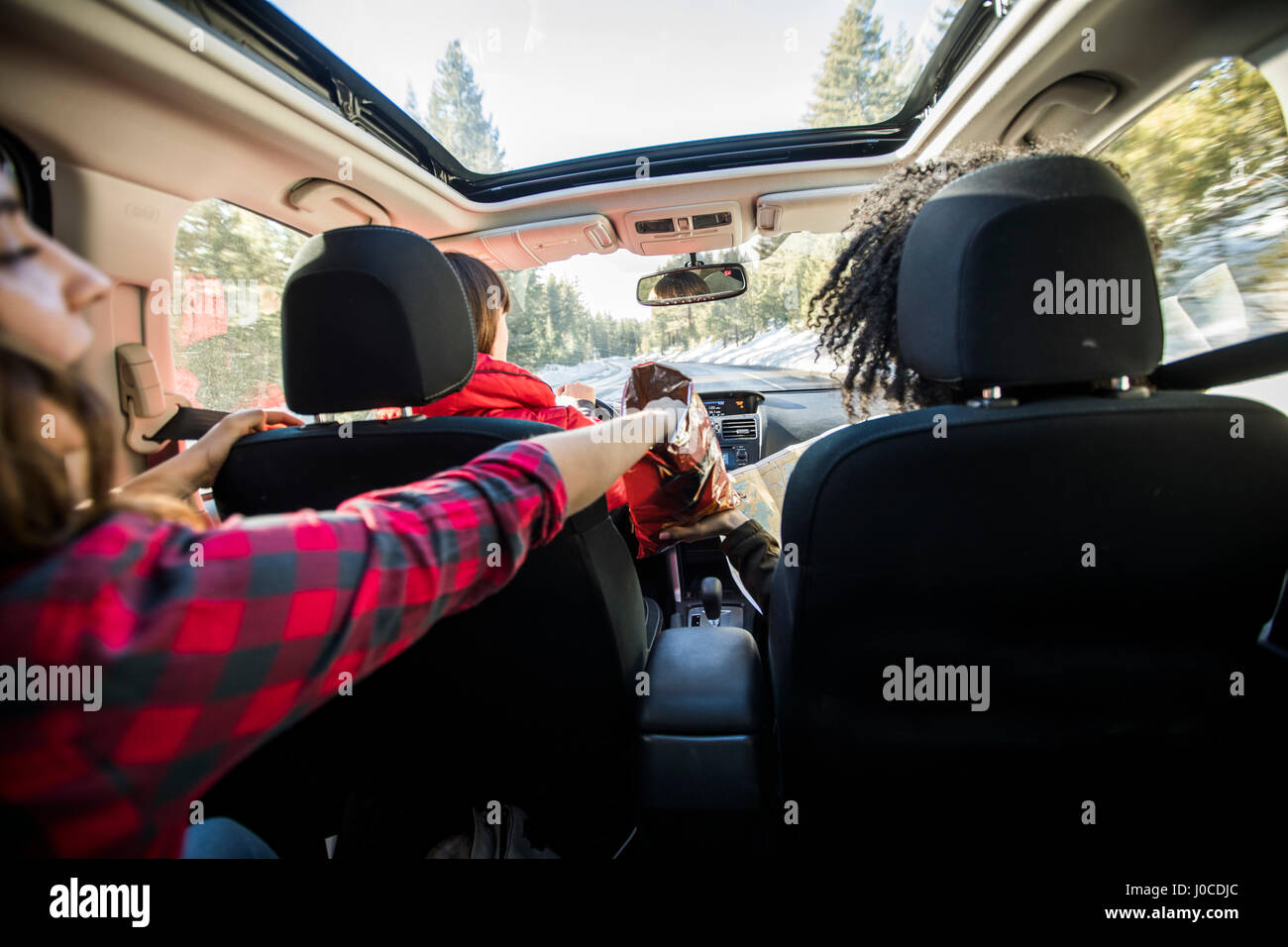 Three friends in moving car, two friends sharing crisps Stock Photo - Alamy