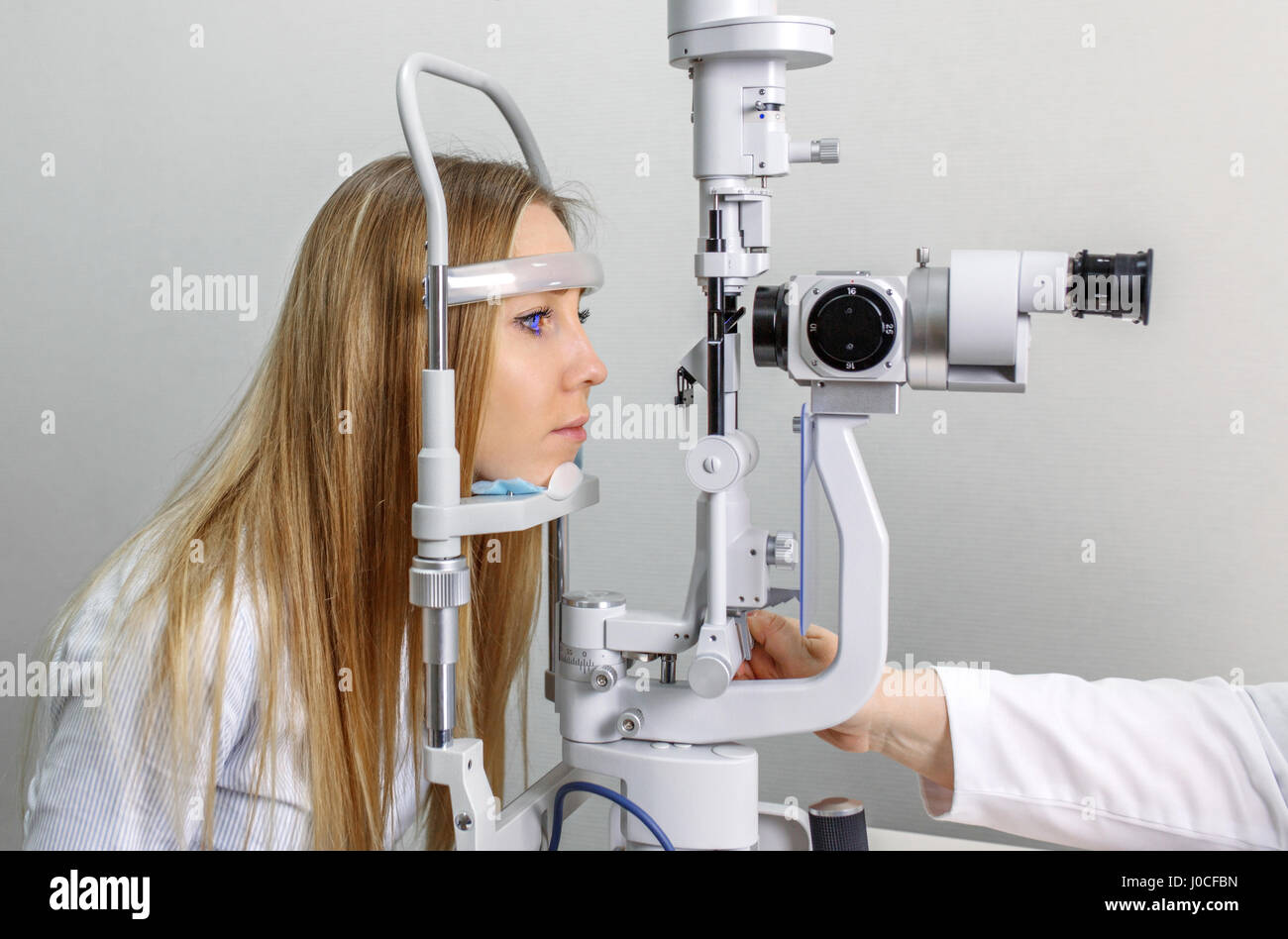 optometry concept - pretty young woman having her eyes examined by an ...