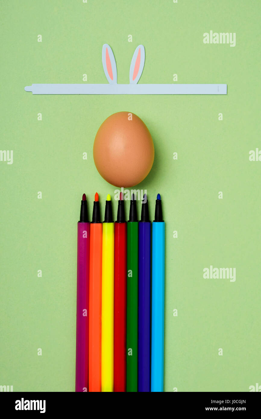 a brown egg with, a band with rabbit ears and marker pens of different ...