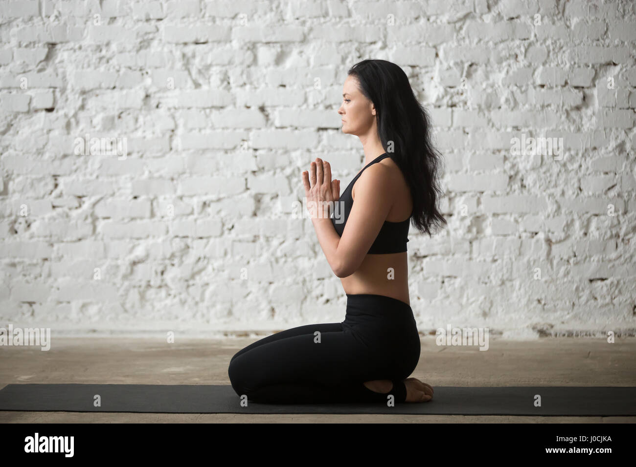 Young yogi woman in seiza pose with namaste, loft background Stock ...