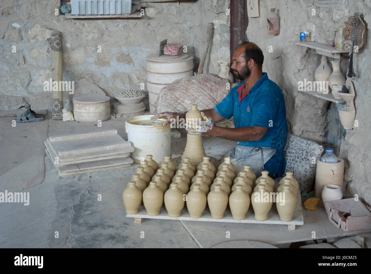 A potter at the A'ali pottery making clay into water pots Stock Photo ...
