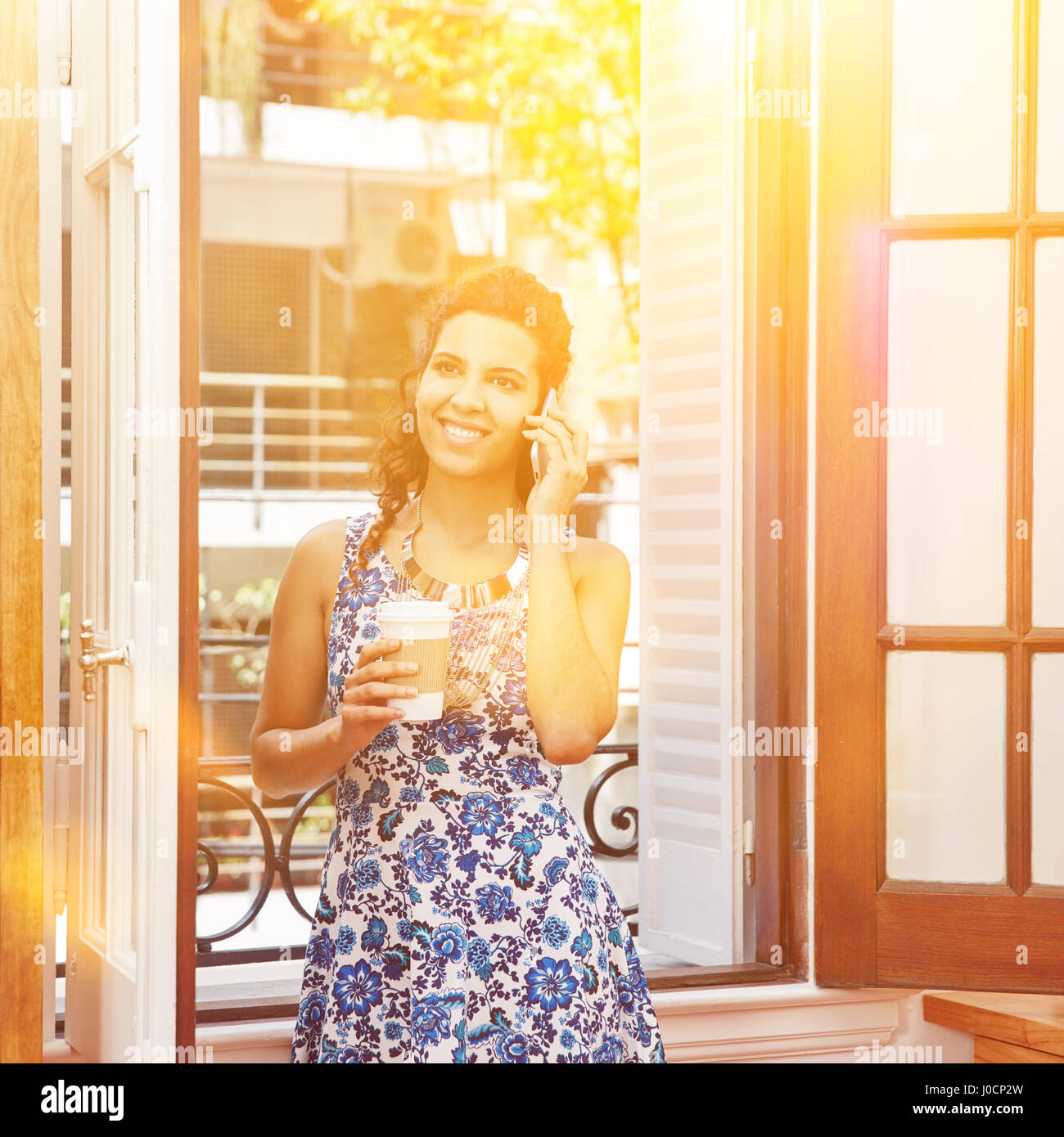 Woman drinking coffee and calling with smartphone during her break ...