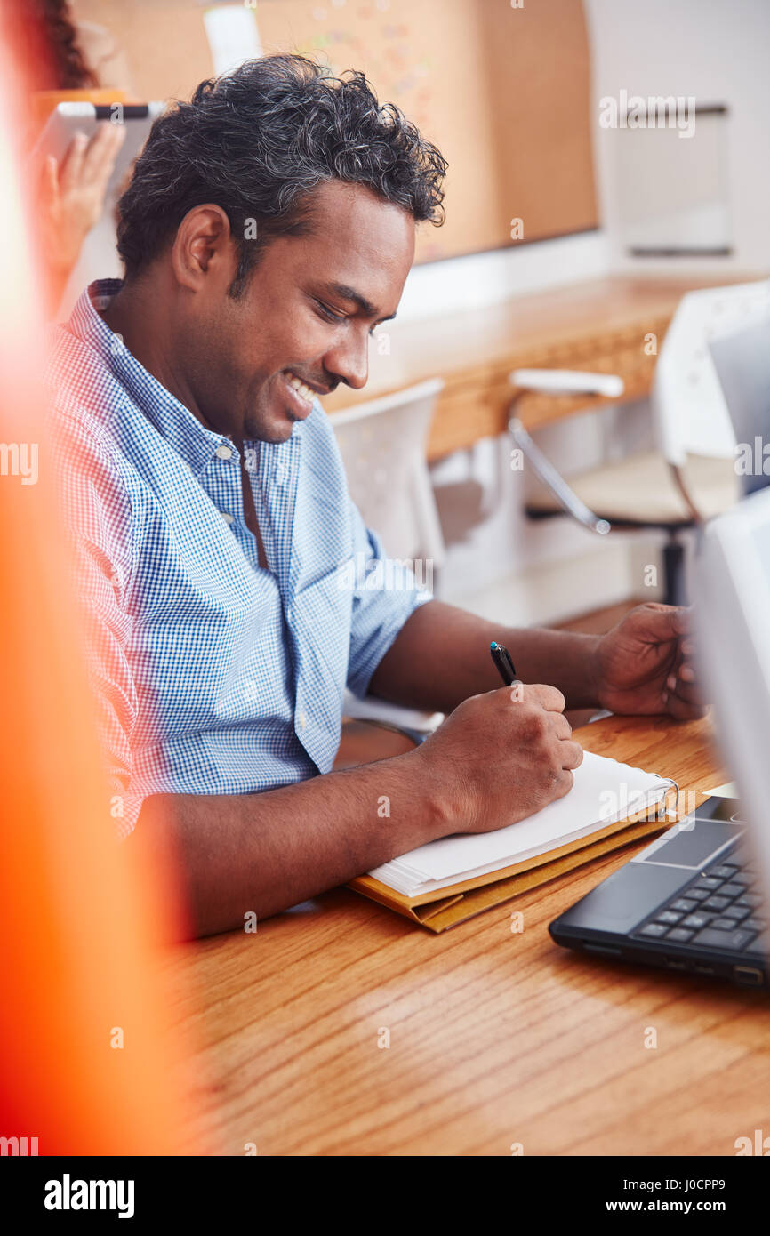 Indian man working in office and taking notes for planning Stock Photo ...