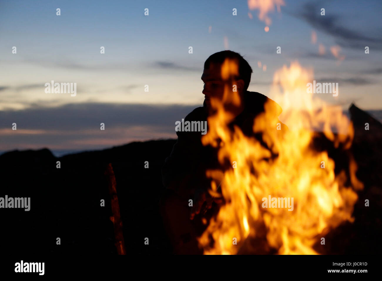 Anthony Henry sits by a driftwood campfire while fishing for lamprey at ...