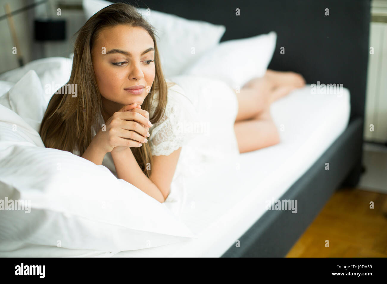 Young woman relaxing in white bed after waking up Stock Photo - Alamy