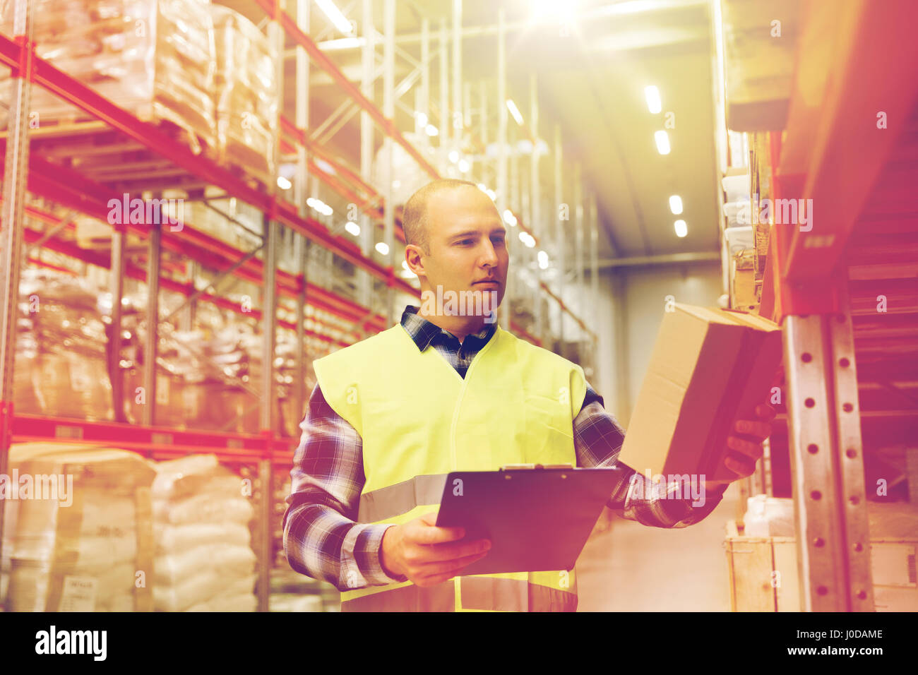 man with clipboard in safety vest at warehouse Stock Photo - Alamy