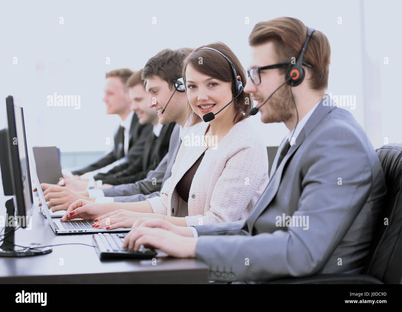 side view:female operator in call center looking at the camera and his ...