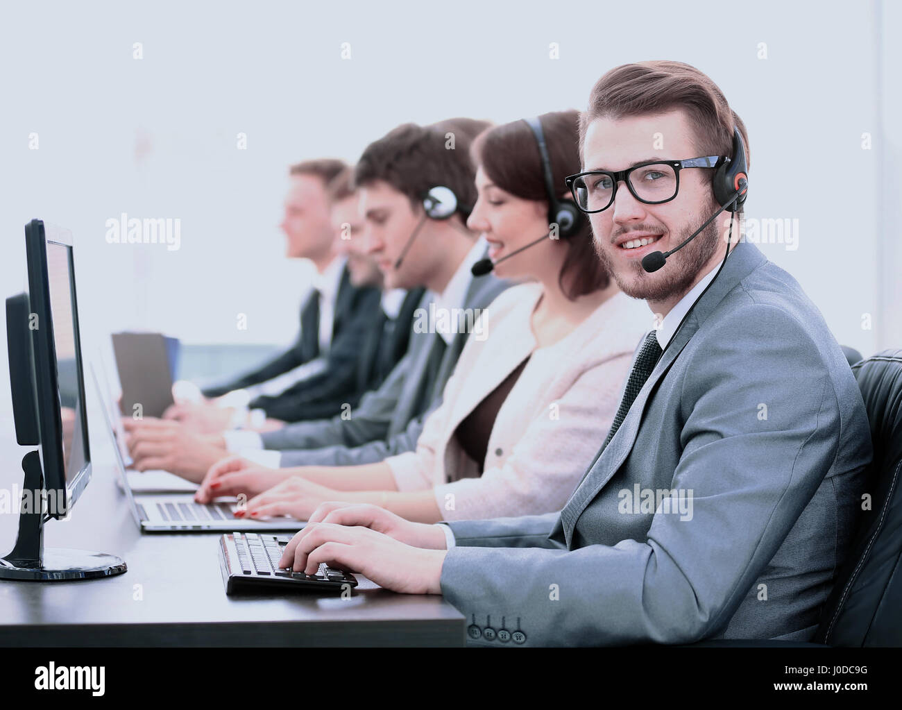 side view: operator in the call center looking at the camera and his ...