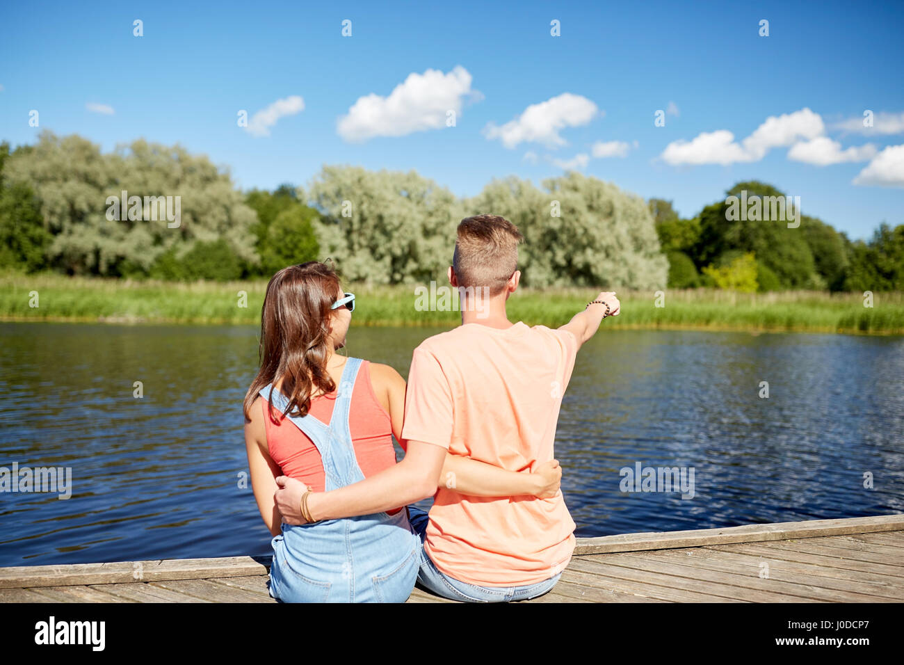 happy couple pointing finger on summer river berth Stock Photo - Alamy