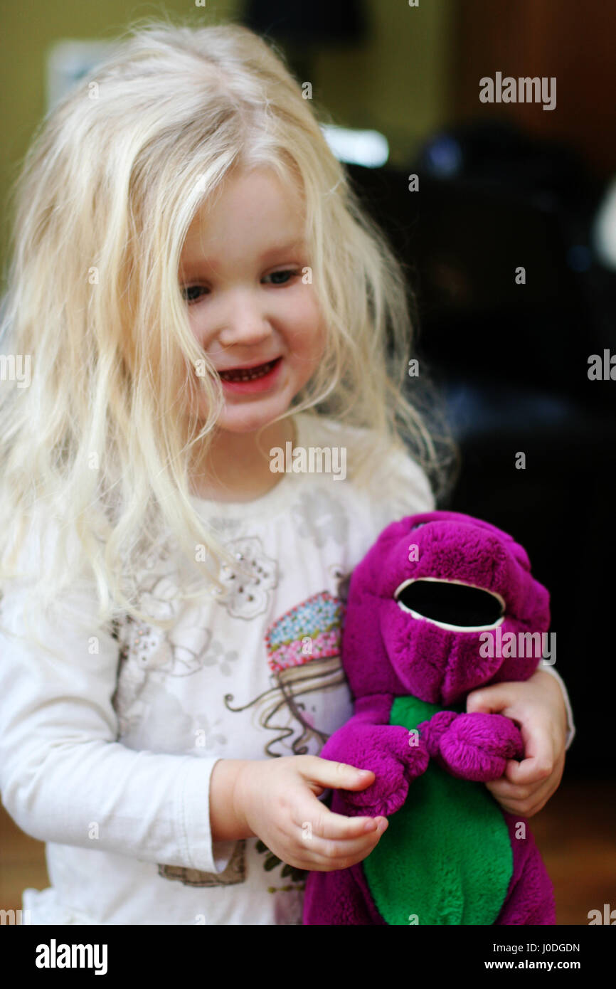 Little two year old blonde child girl playing, loving barney soft toy ...