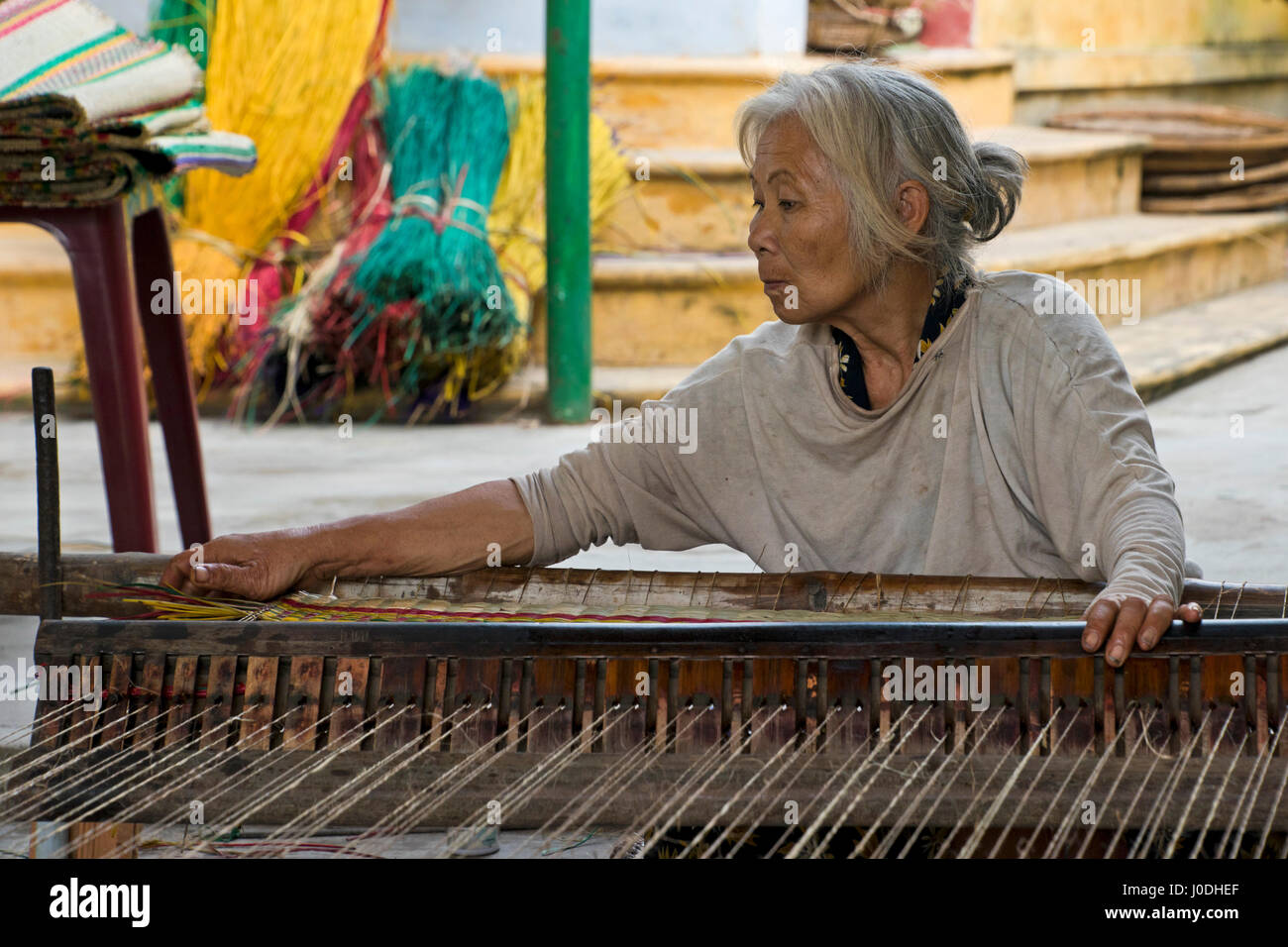 Horizontal portrait of an old lady weaving traditional Vietnamese ...