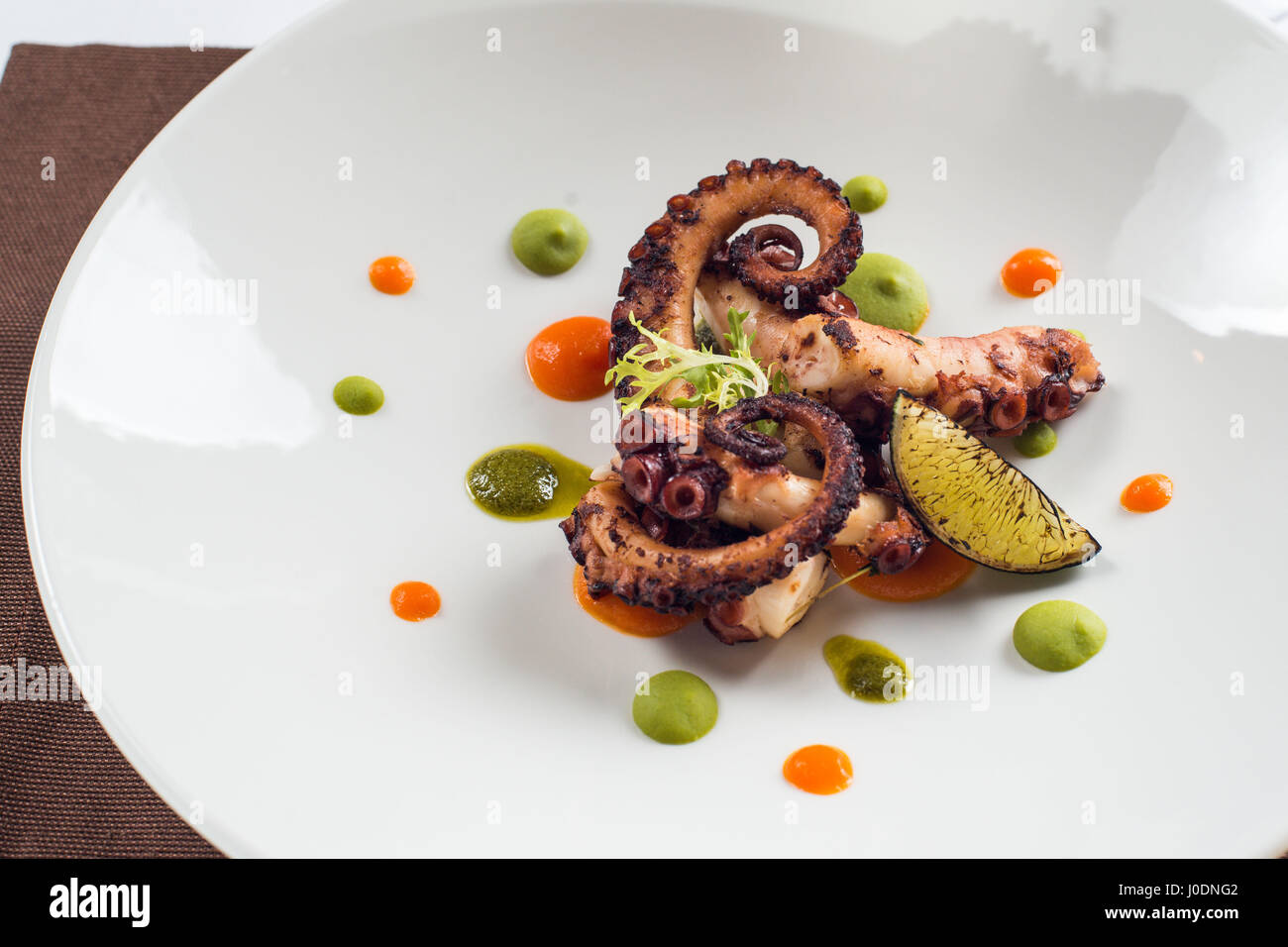 grilled octopus cut with a knife for food on a white plate Stock Photo ...