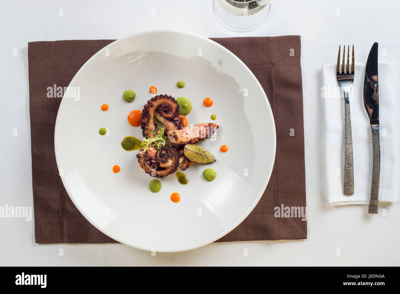 grilled octopus cut with a knife for food on a white plate Stock Photo ...