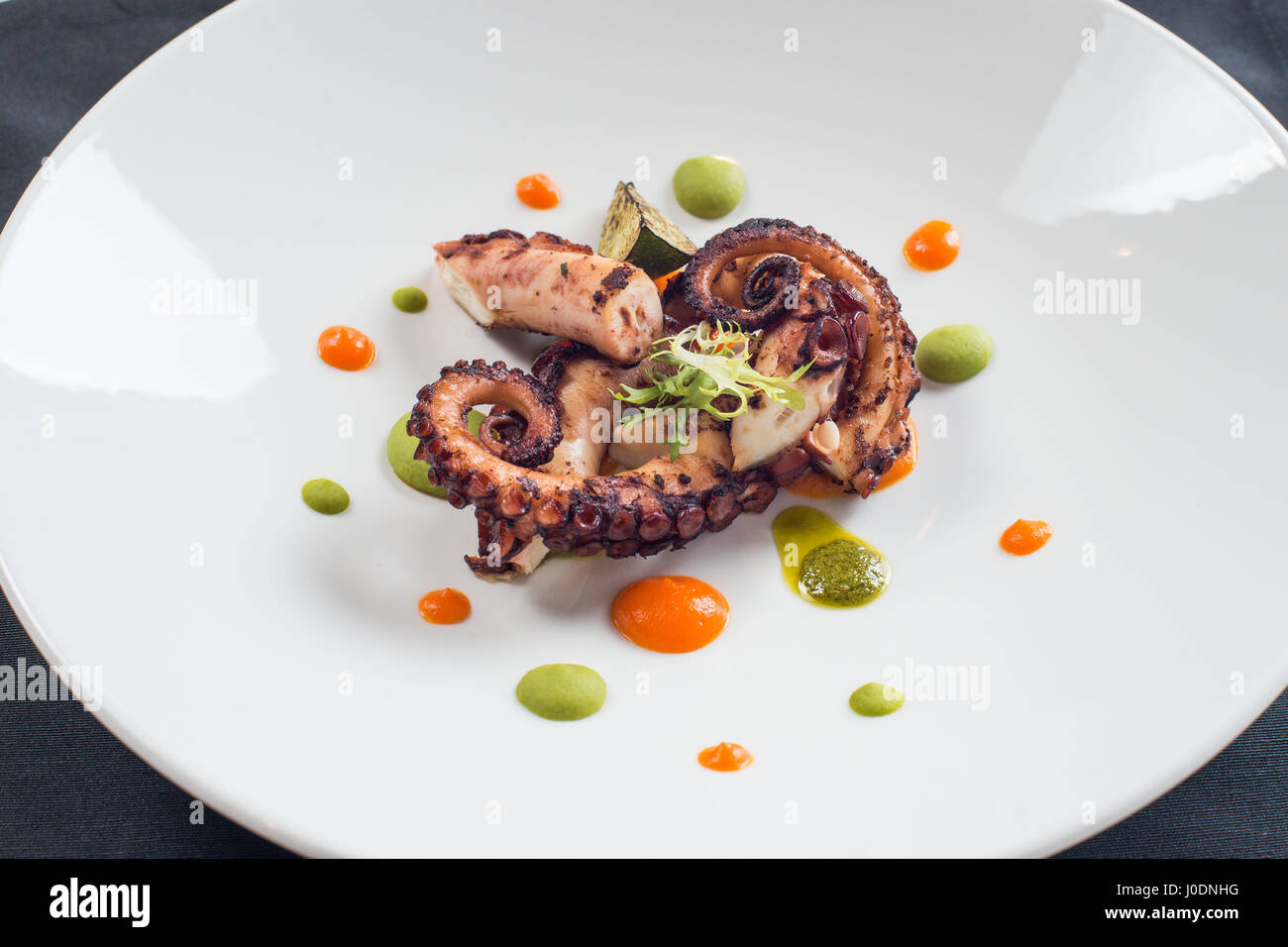 grilled octopus cut with a knife for food on a white plate Stock Photo ...