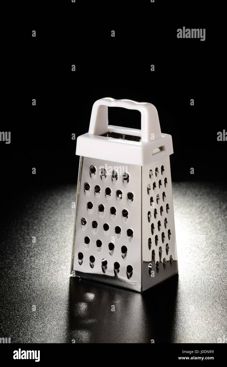 Metal grater on black grained background Stock Photo - Alamy