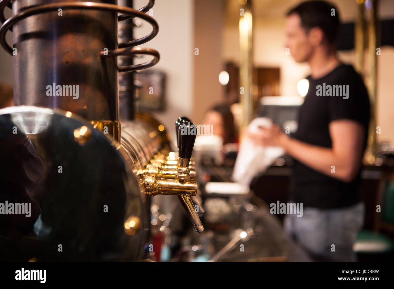 Lot of vintage Golden beer taps in the bar with the bartender in the ...