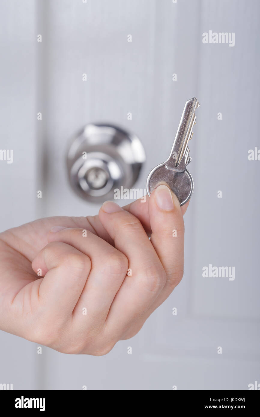 key in hand with door knob and white door background Stock Photo - Alamy