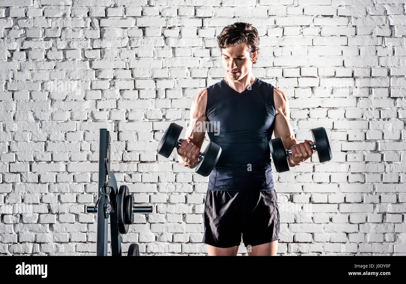 Young sportive man in sportswear exercising with dumbbells in gym Stock ...