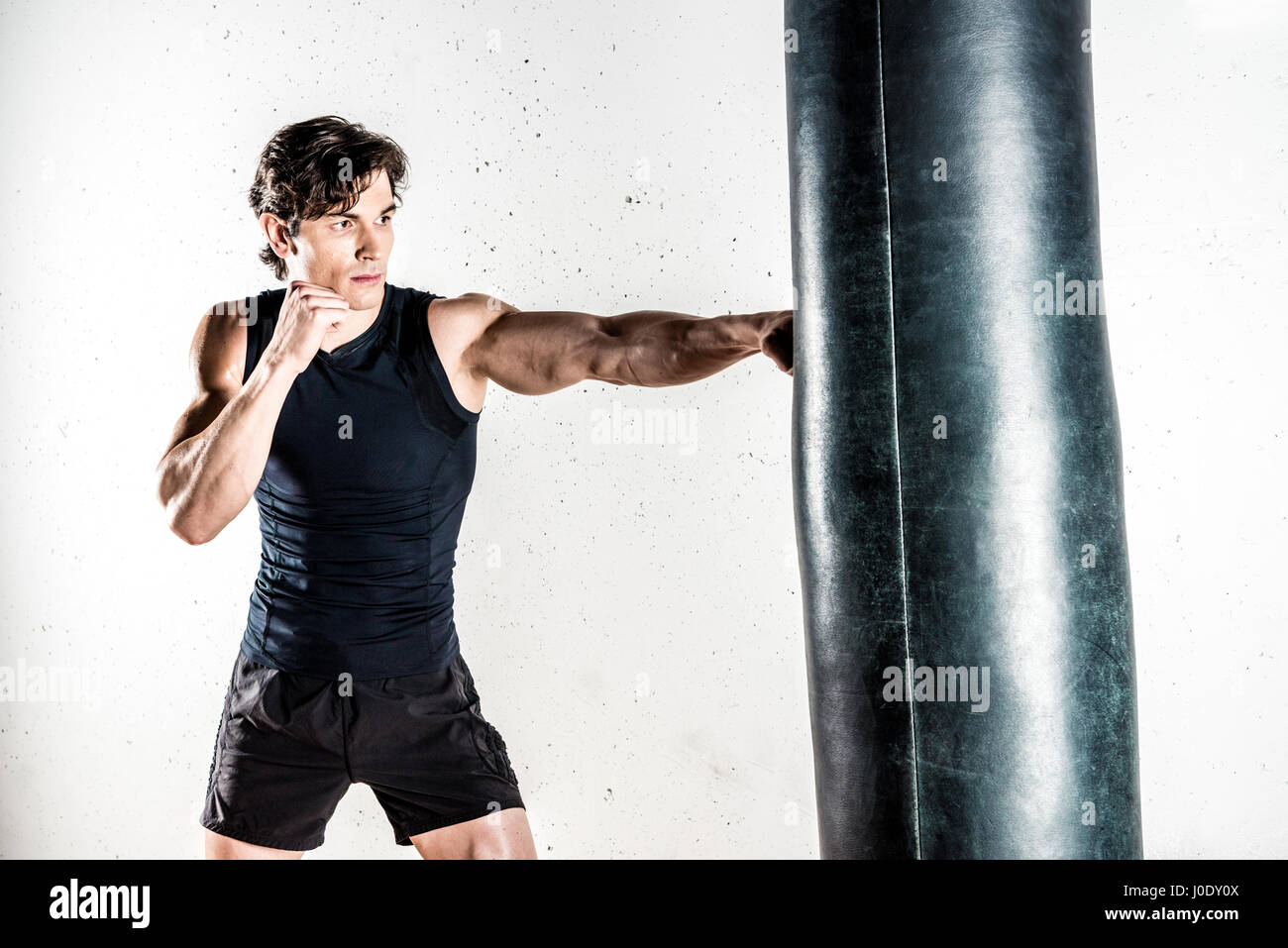 Muscular male kickboxer in sportswear boxing in punching bag Stock ...