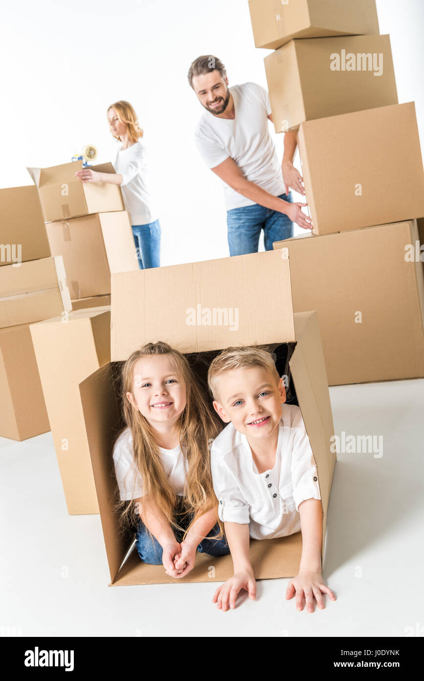 Cute little kids smiling in cardboard box while parents packing boxes ...