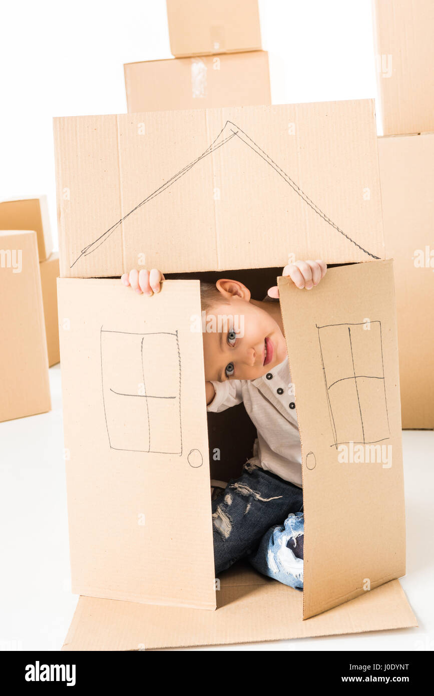 Cute little boy sittling inside of cardboard box with house drawed on ...
