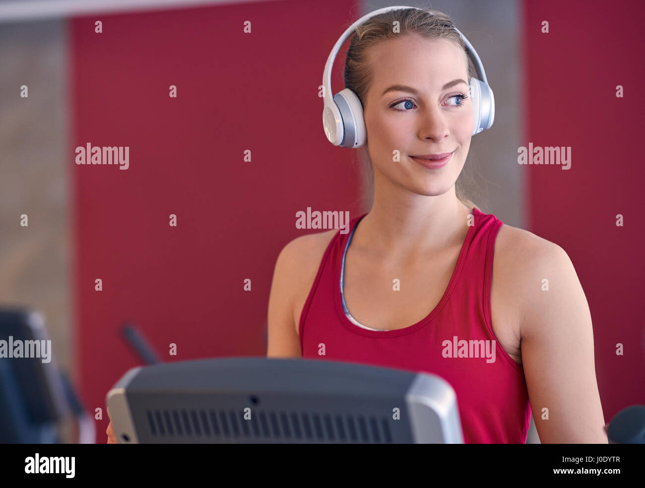 Smiling young blond woman wearing headphone in gym Stock Photo - Alamy