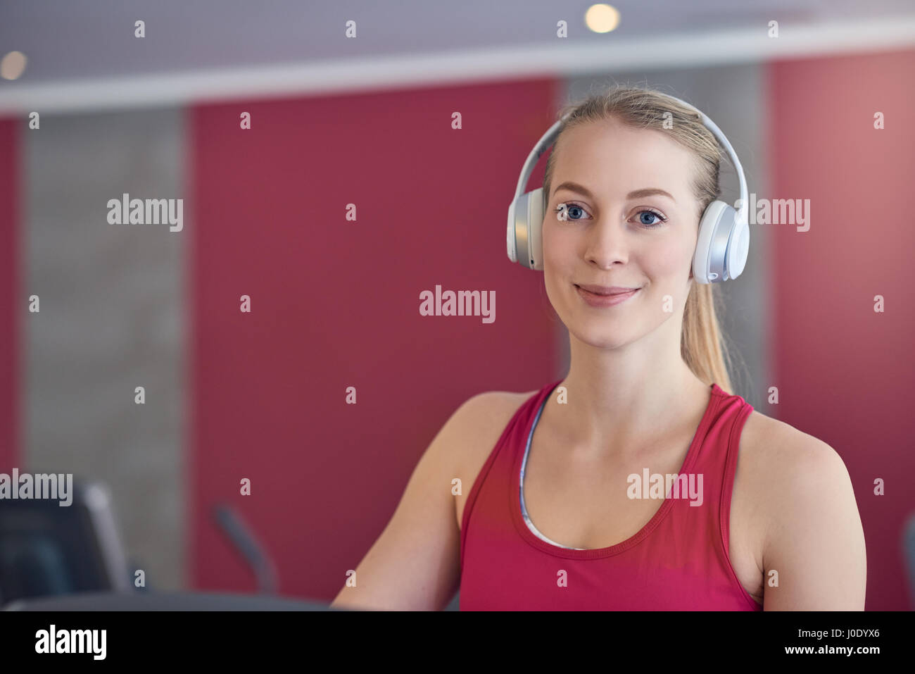 Smiling young blond woman wearing headphone in gym Stock Photo - Alamy