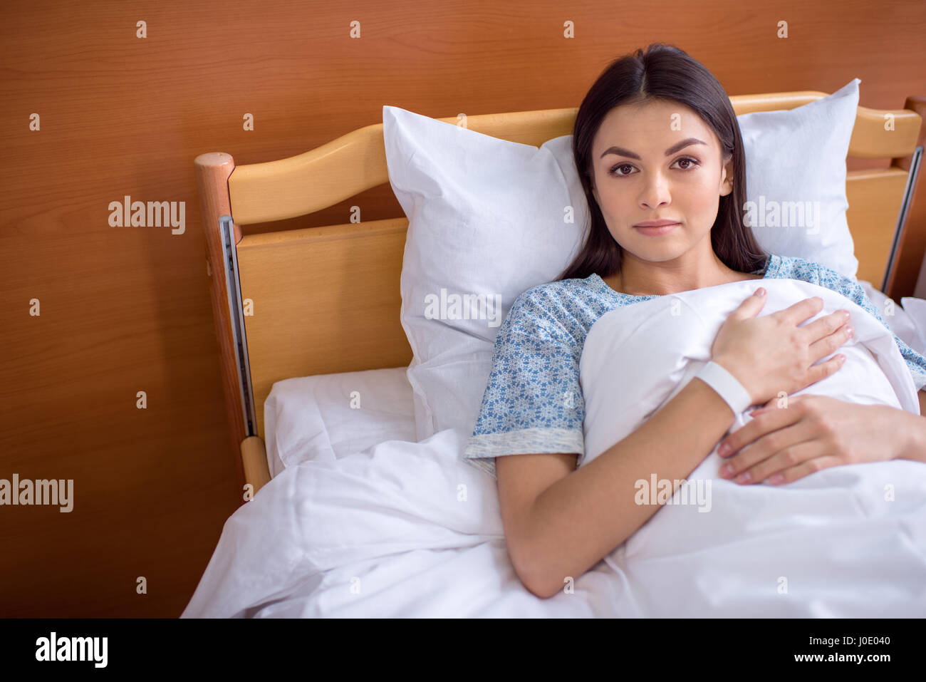 Young female patient lying in hospital bed and looking at camera Stock ...