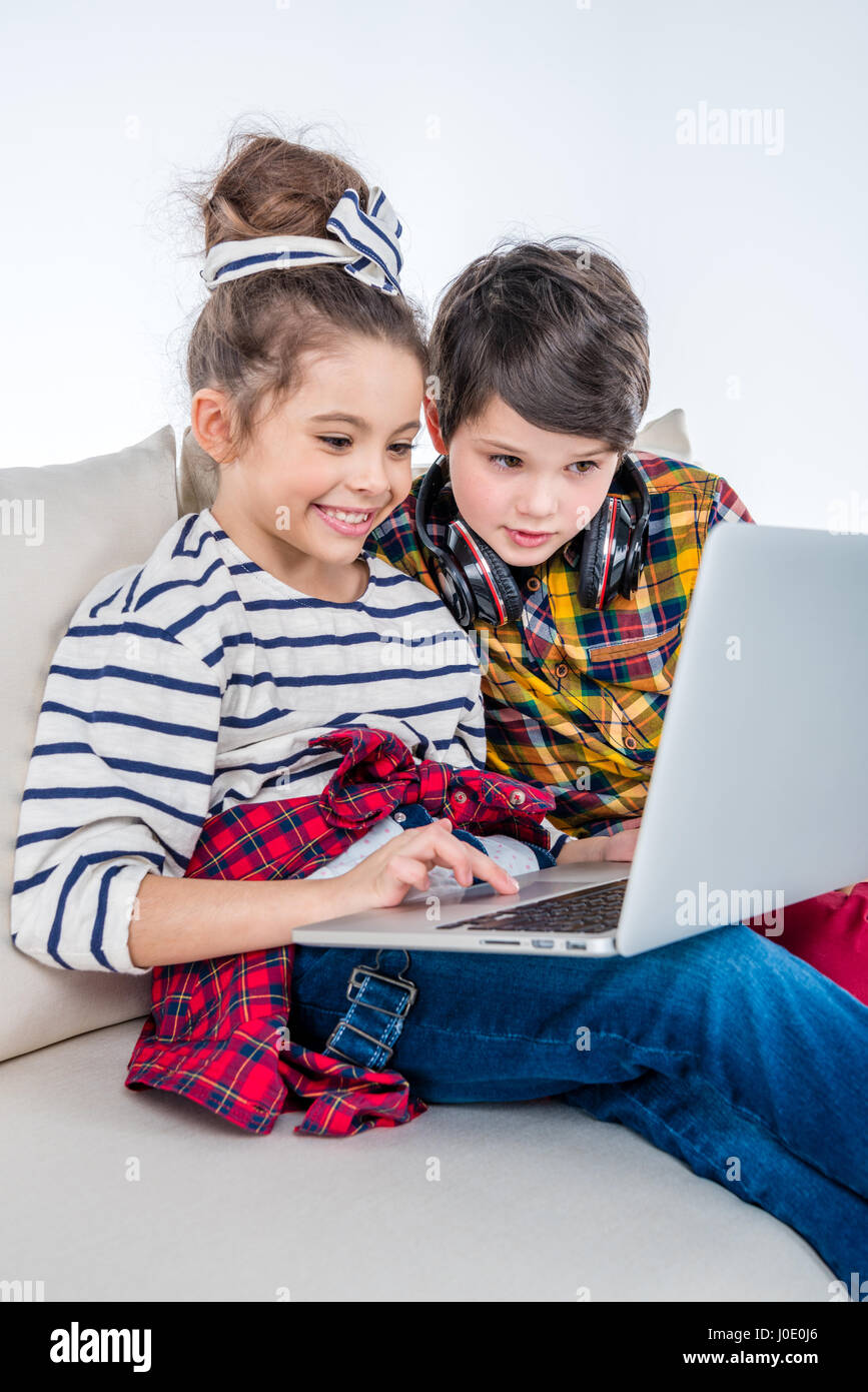 Children using laptop and sitting on sofa on gray Stock Photo - Alamy