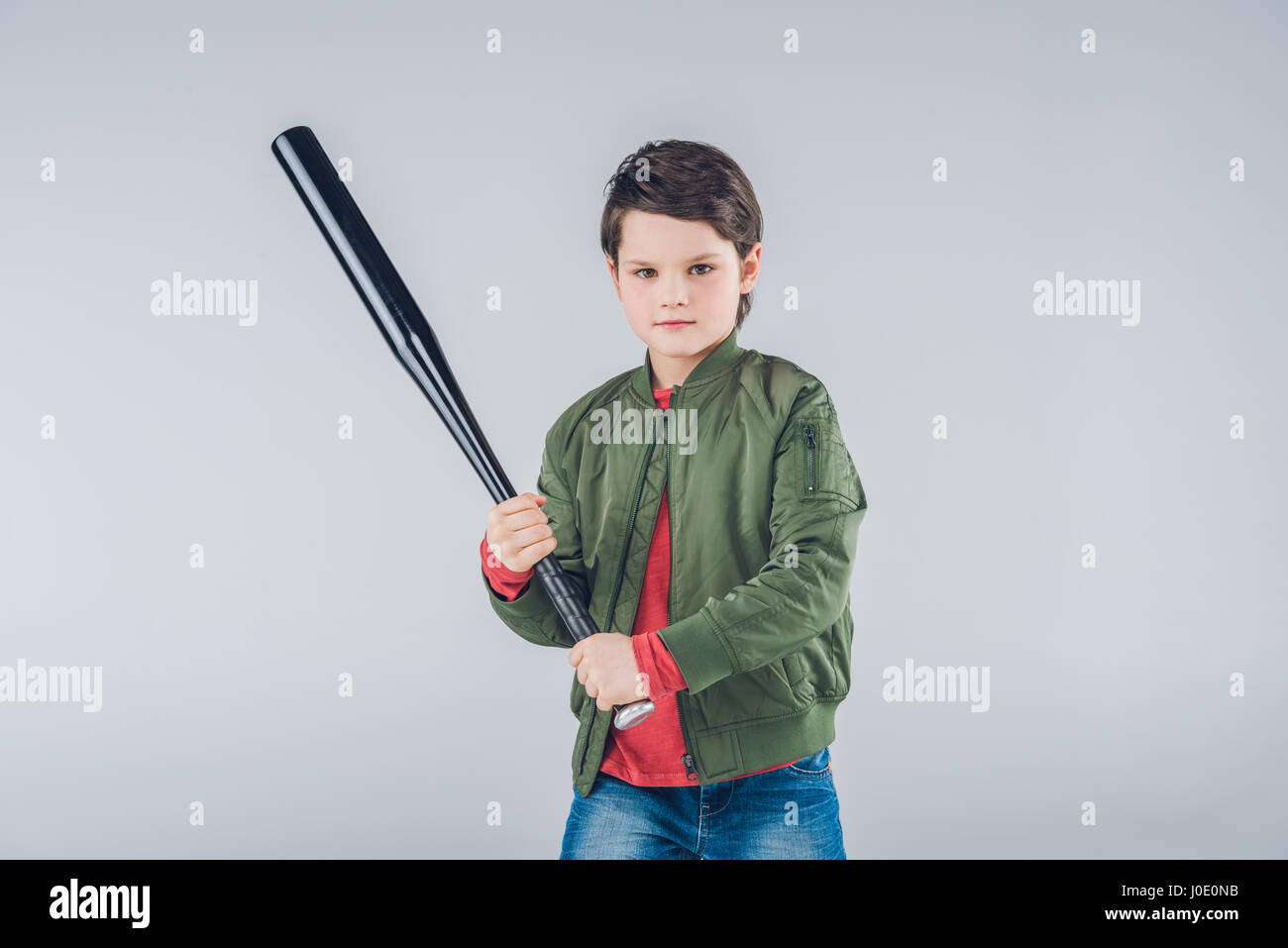 Boy with baseball bat standing on gray Stock Photo - Alamy