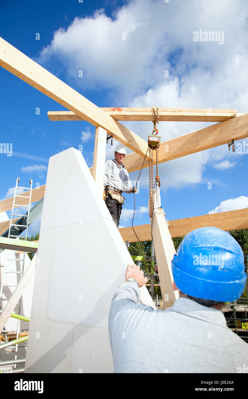 construction workers at work with wooden roof construction of a new ...