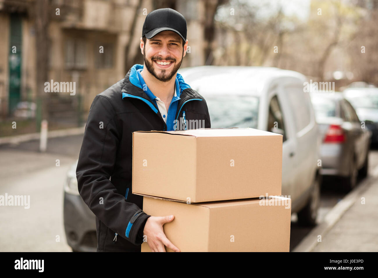Delivery man with cap and cardboard in hands Stock Photo - Alamy
